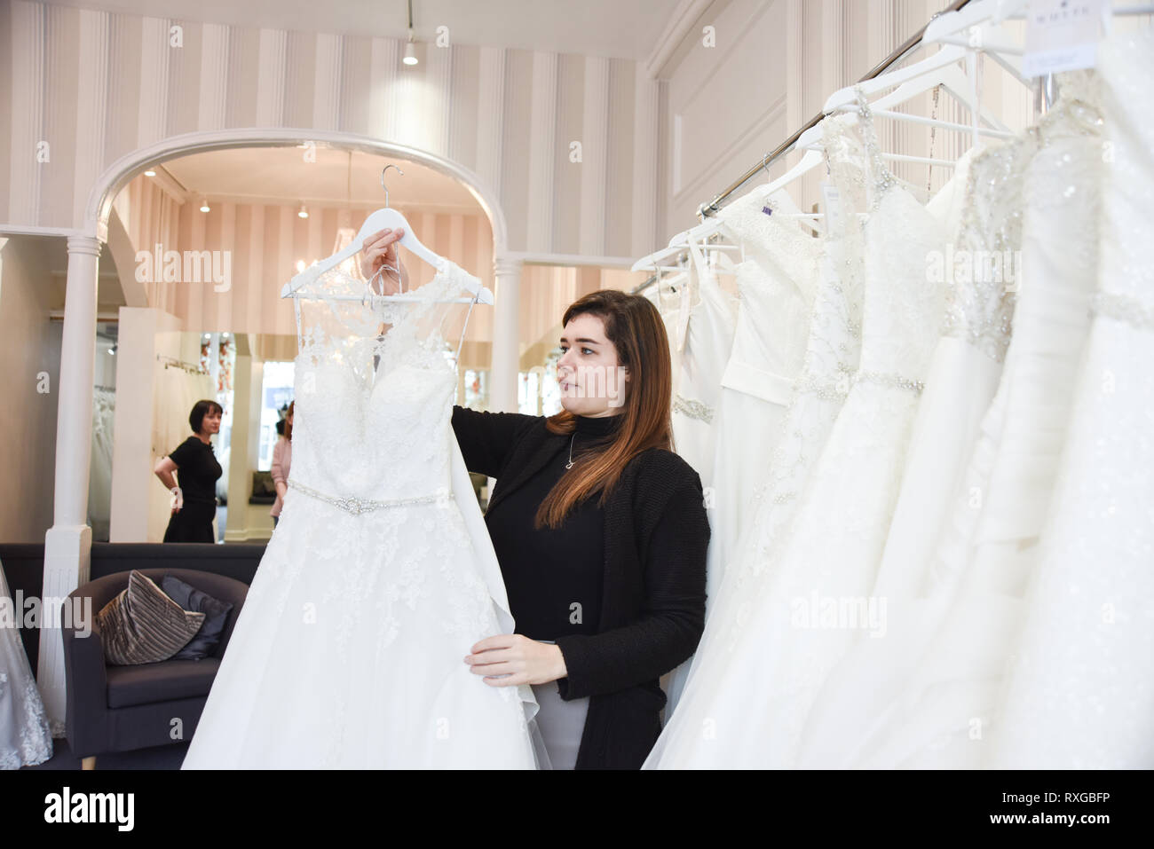 2 shop assistants are helping a pretty red haired girl in a Wedding ...