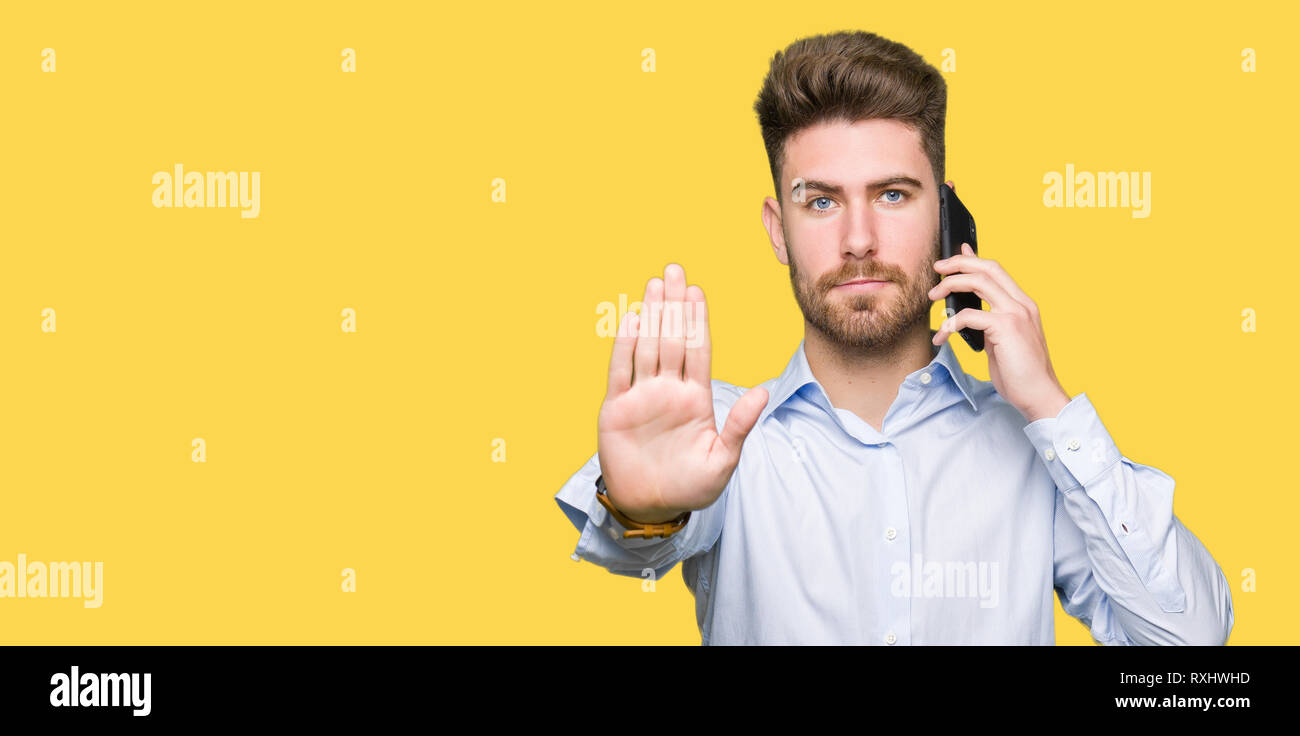 Young handsome man business talking on smartphone with open hand doing ...