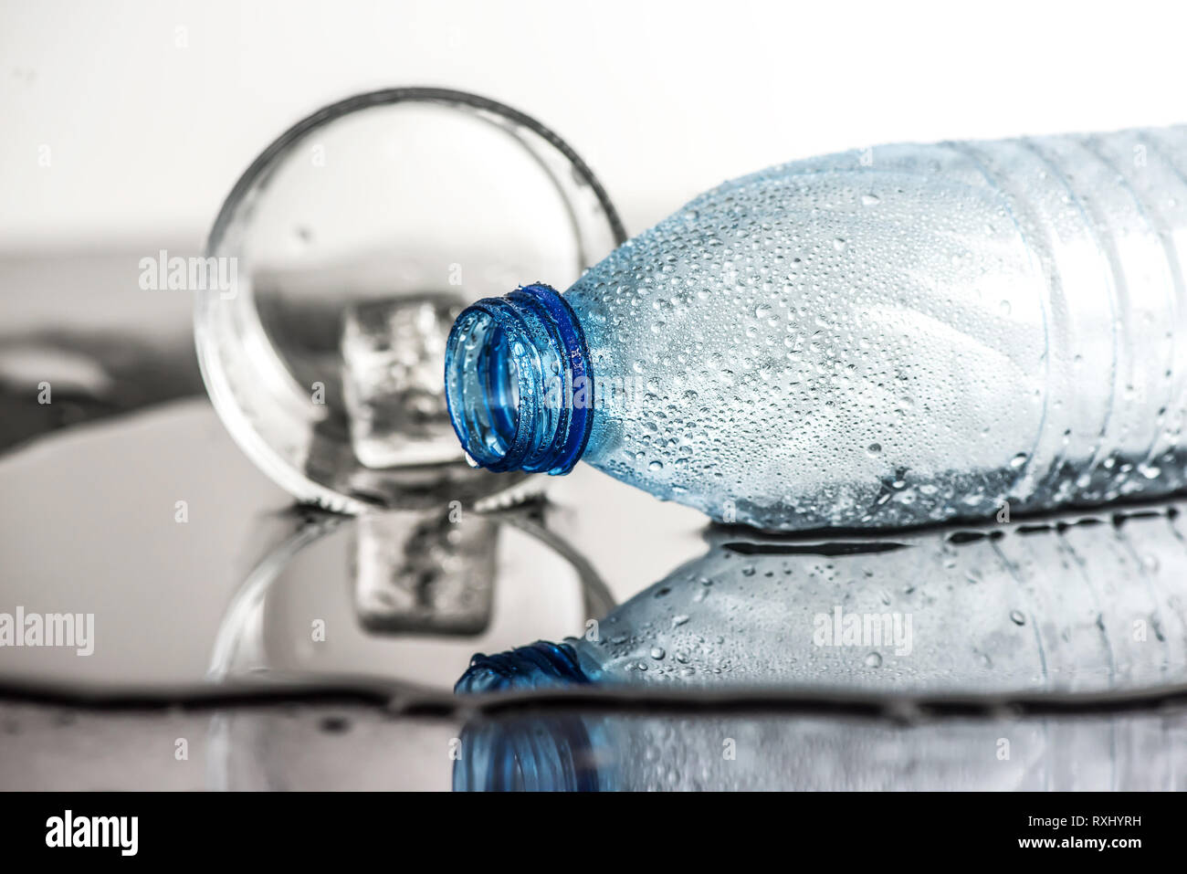 Wet background with a glass of water and empty plastic bottles Stock ...