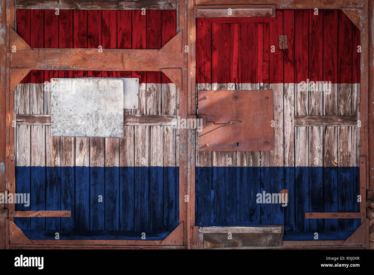 Close-up of old warehouse gate with national flag of Netherlands. The ...