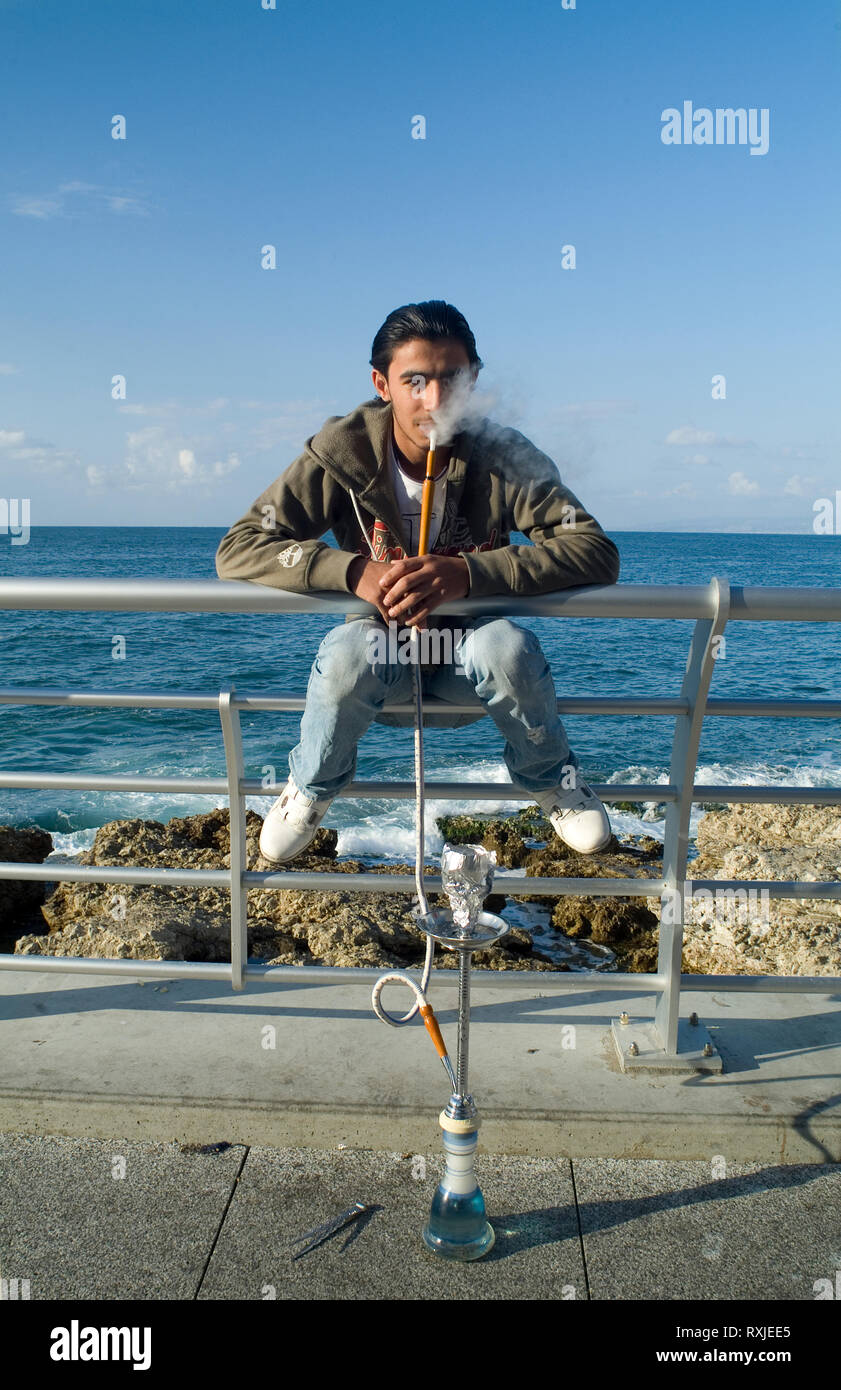 A young man smoking a nargileh on Beirut's Corniche, a spacious palm ...