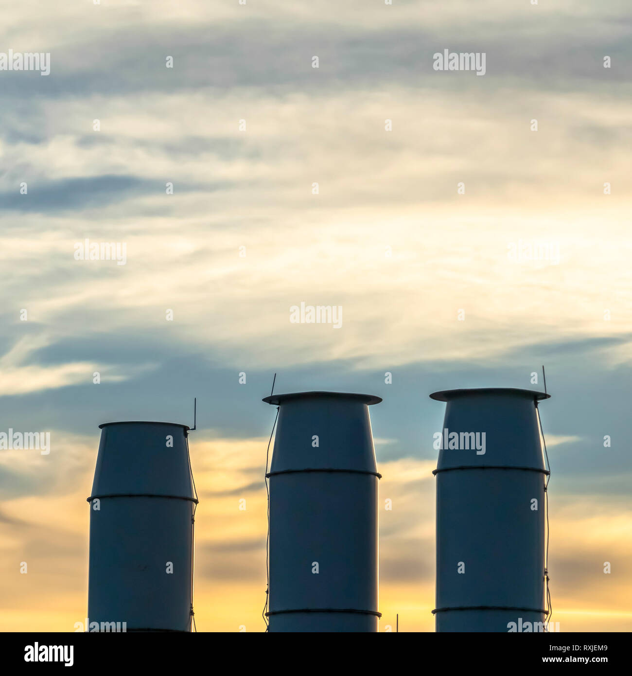 Smokestacks with cloudy sky background at sunset Stock Photo - Alamy