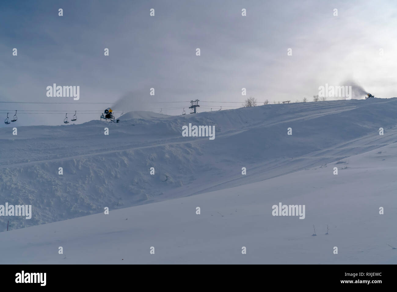 Snow covered slope with snow cannons and ski lifts Stock Photo - Alamy