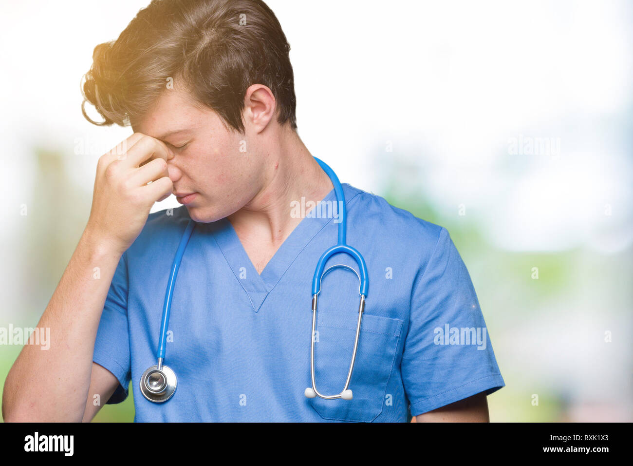 Young doctor wearing medical uniform over isolated background tired ...