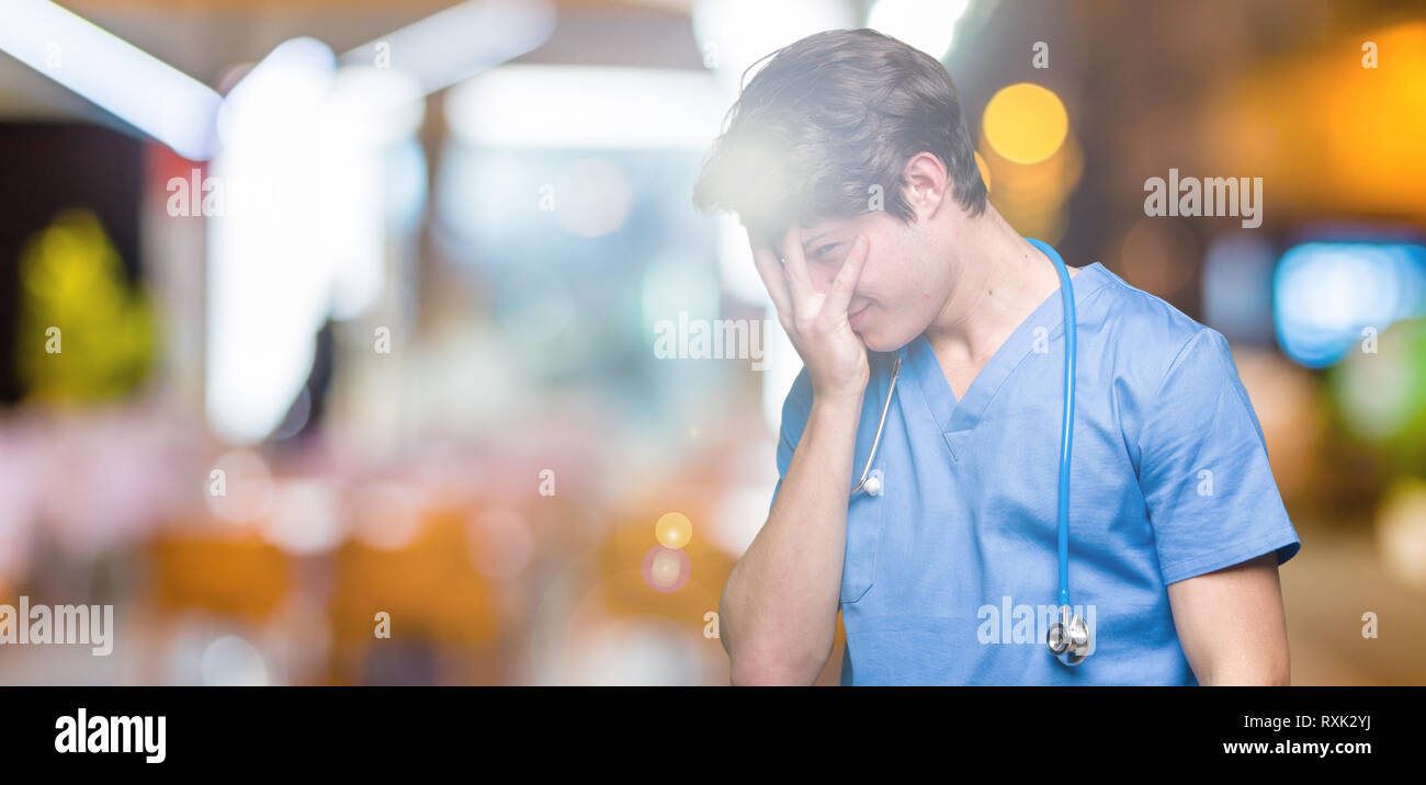 Young doctor wearing medical uniform over isolated background with sad ...