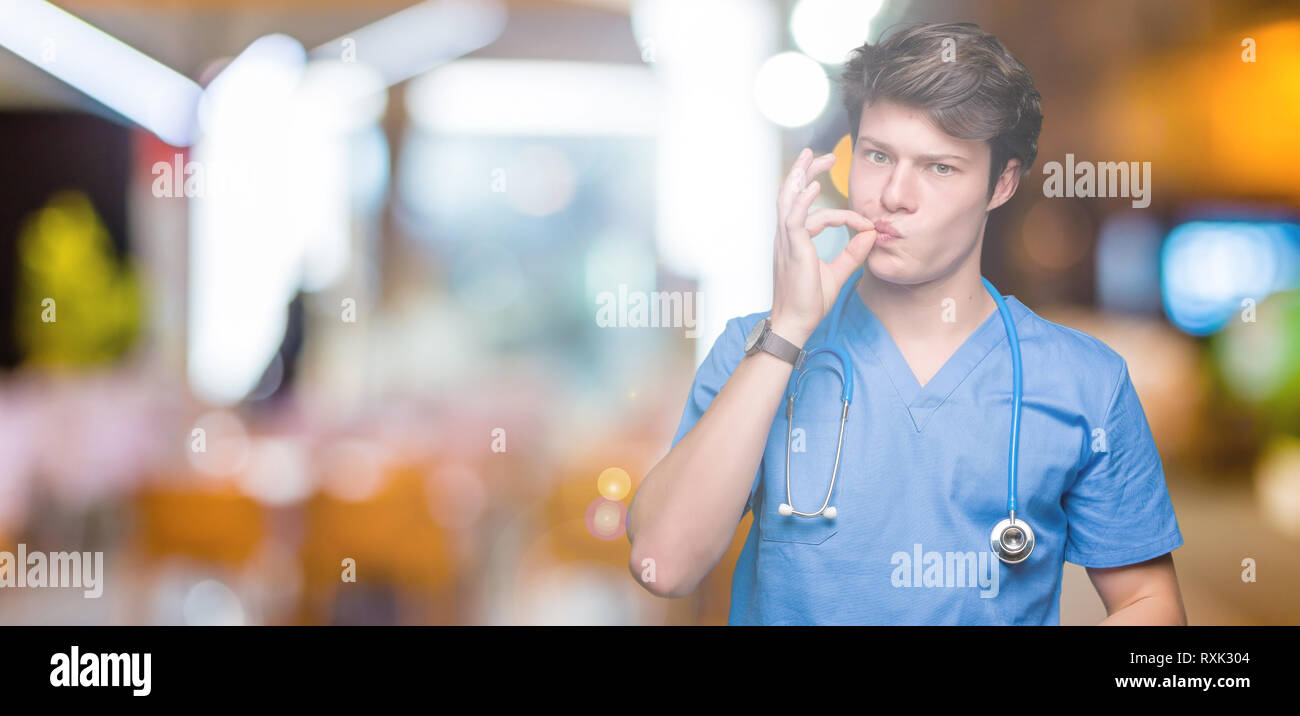 Young doctor wearing medical uniform over isolated background mouth and ...