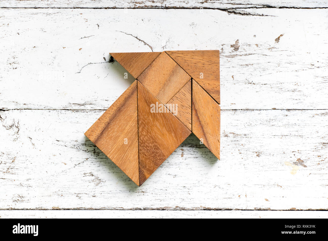 Tangram puzzle in direction arrow shape on old white wood background ...