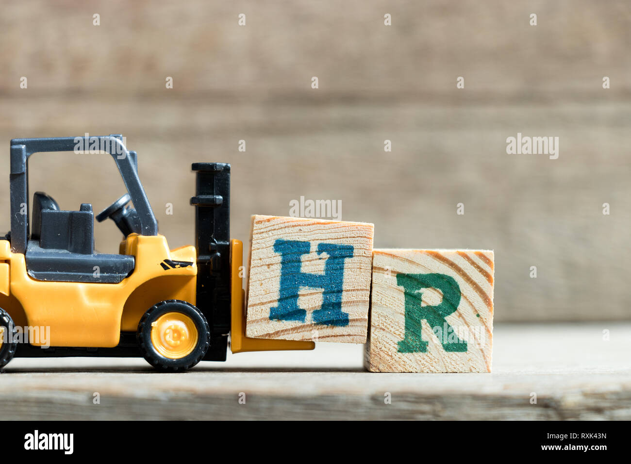 Toy yellow forklift hold letter block H to complete word HR ...