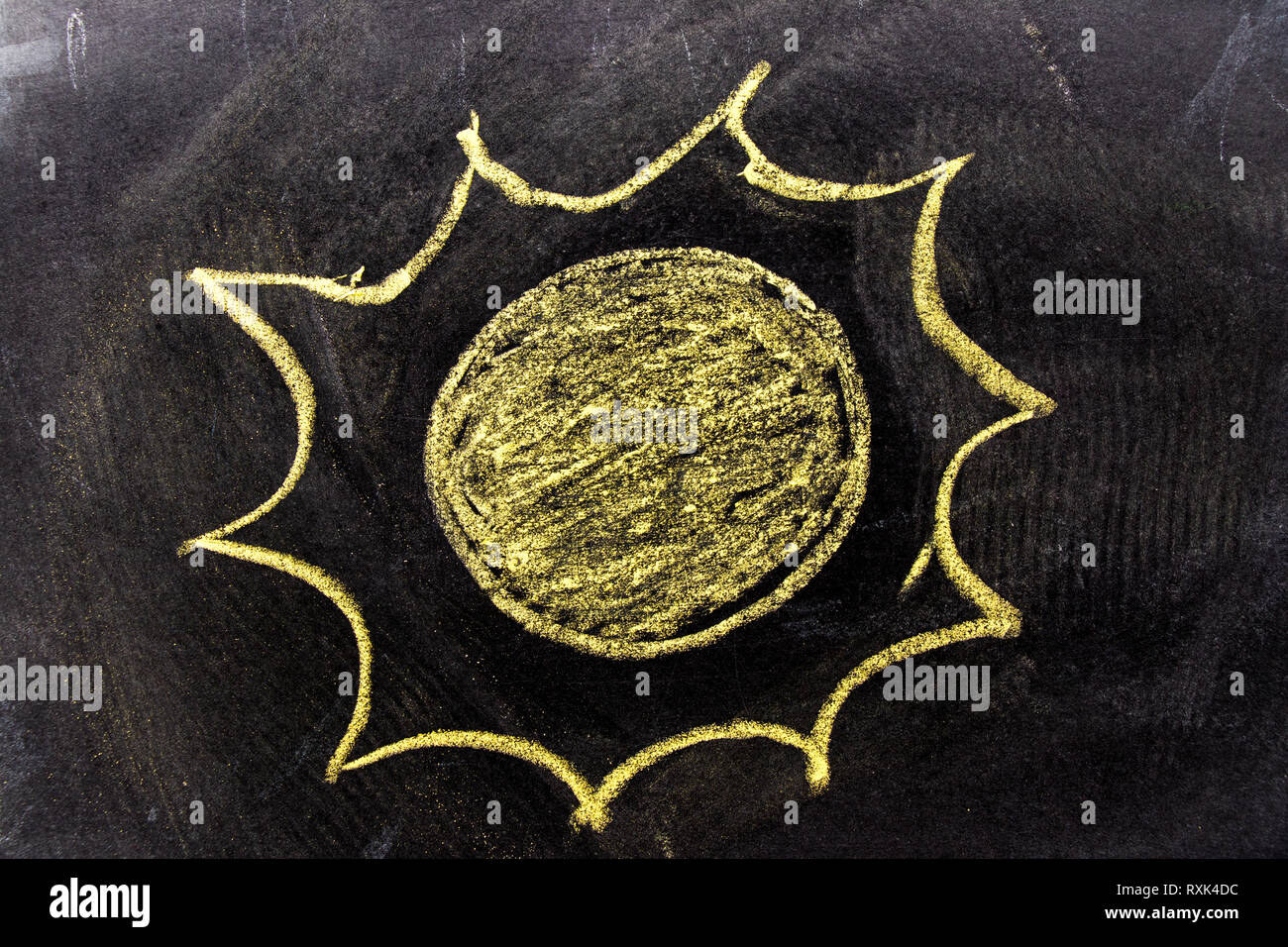 Yellow color chak hand drawing in sun with ray shape on blackboard ...