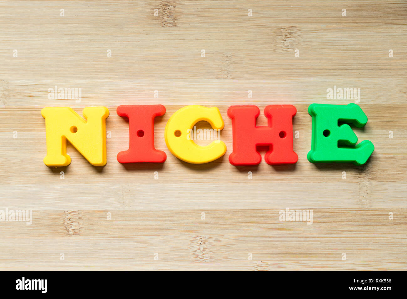 Color plastic alphabet in word niche on wood background Stock Photo - Alamy