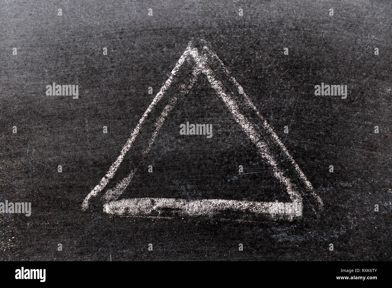 White color chak hand drawing in triangle geometric shape on blackboard ...