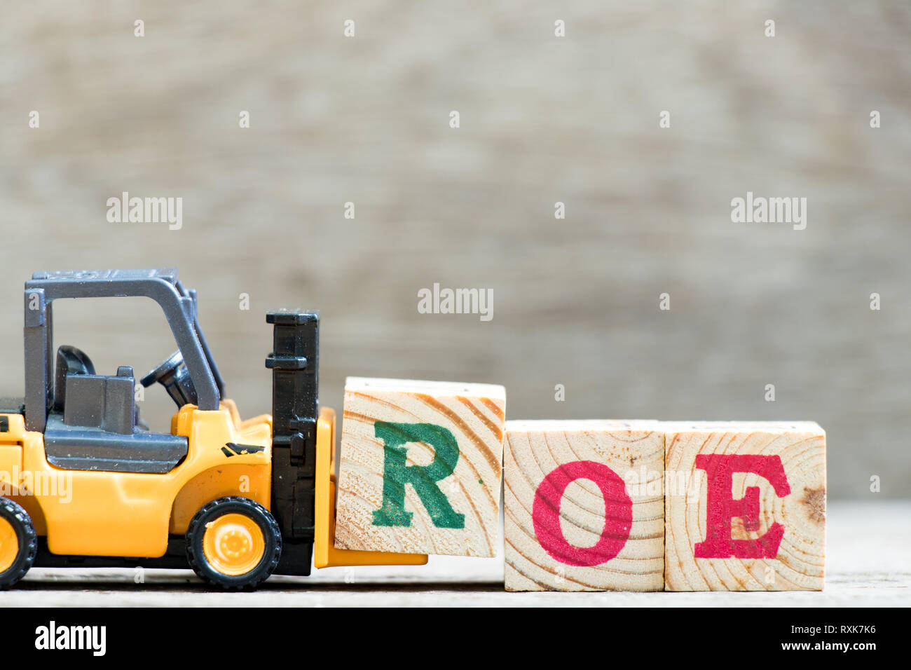 Toy forklift hold letter block in word ROE (abbreviation of return on ...
