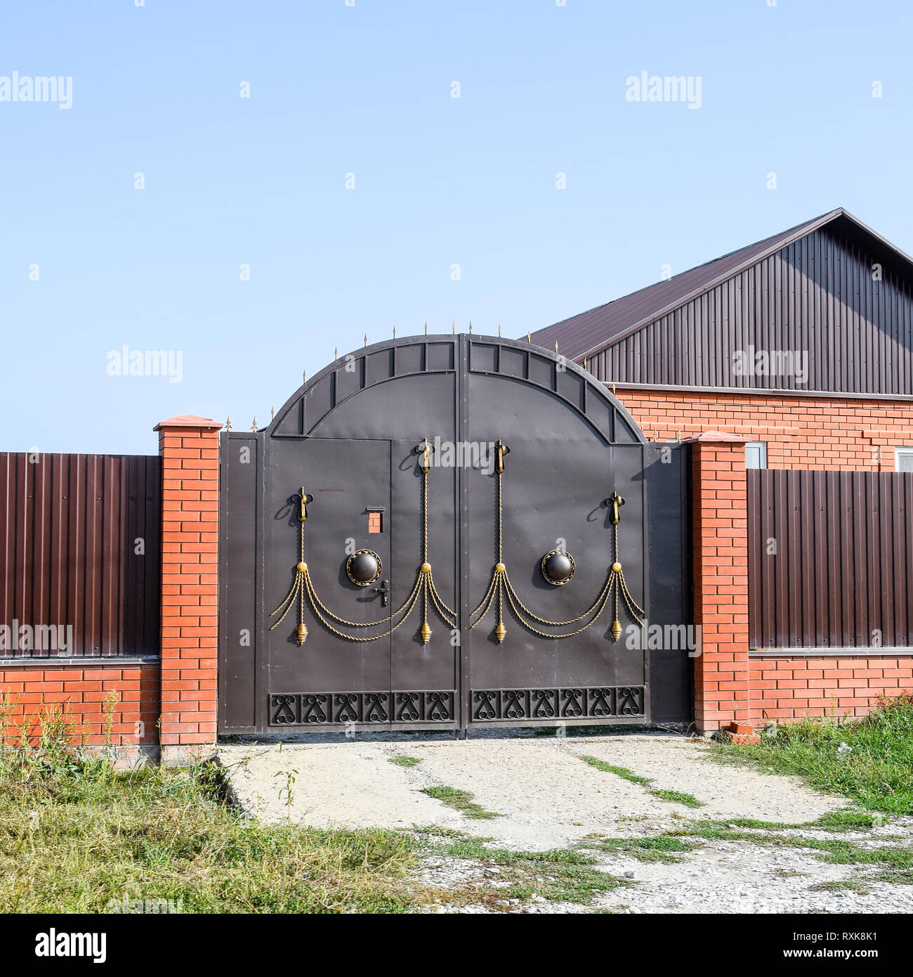 Brick house with a fence and gates. View of a new built-up fence and a ...