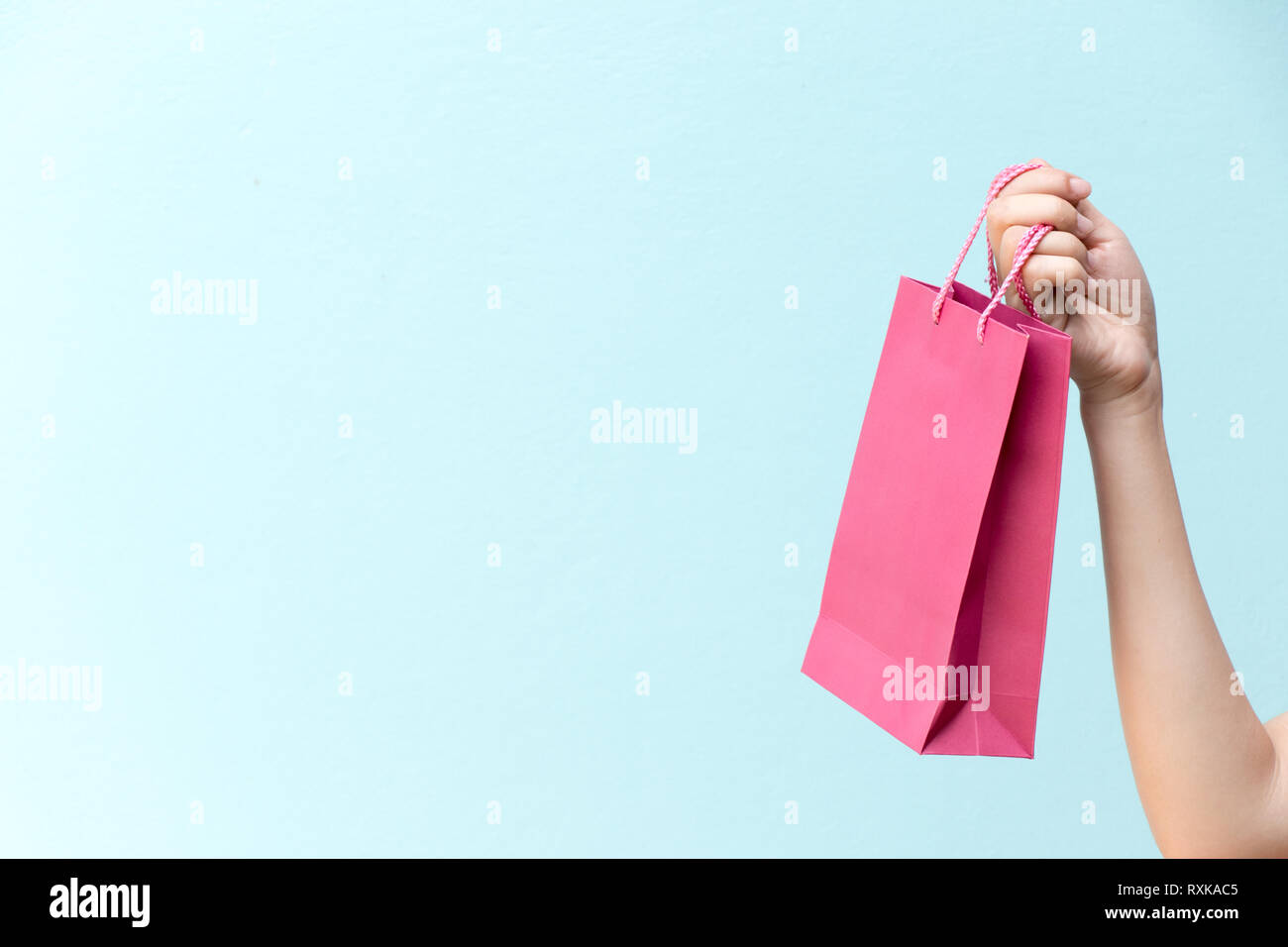 Hand of business woman hold pink shopping bag on blue concrete ...
