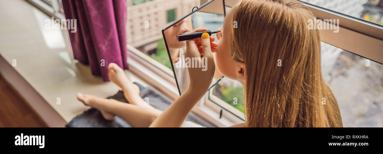 Young woman does makeup sitting by the window with a panoramic view of ...