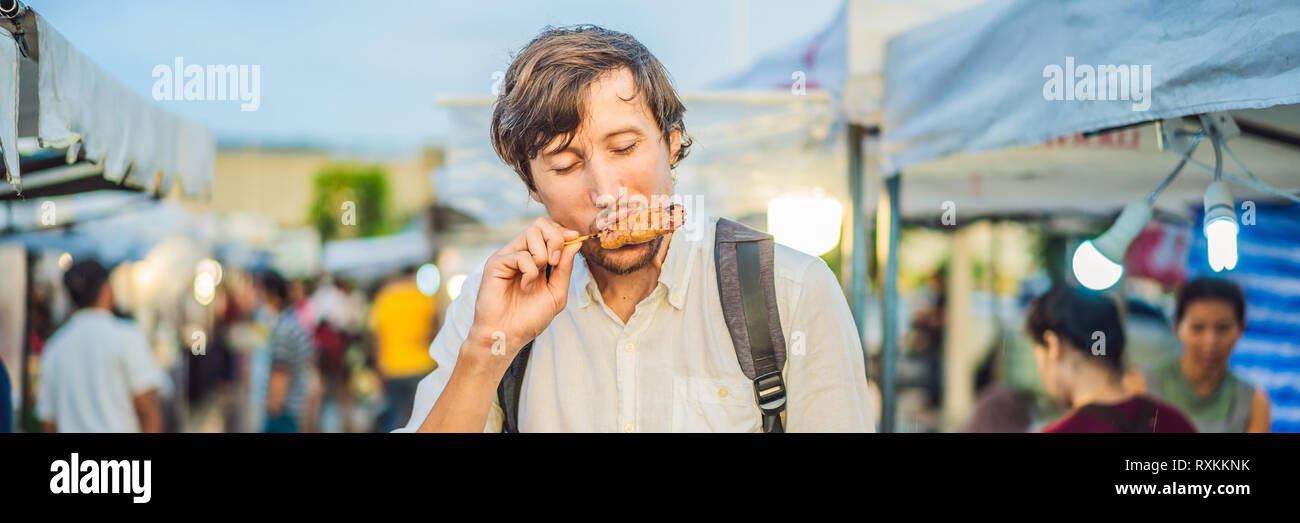 Young man tourist on Walking street Asian food market. BANNER, LONG ...