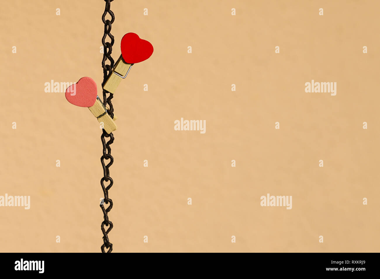 Love concept: Two red and pink clips with heart shape on a steel chain ...