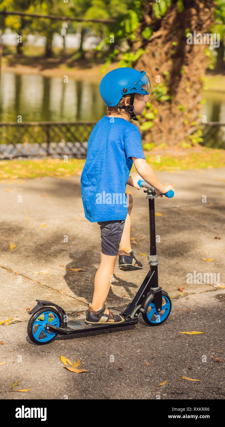 Boy riding scooters, outdoor in the park, summertime. Kids are happy ...
