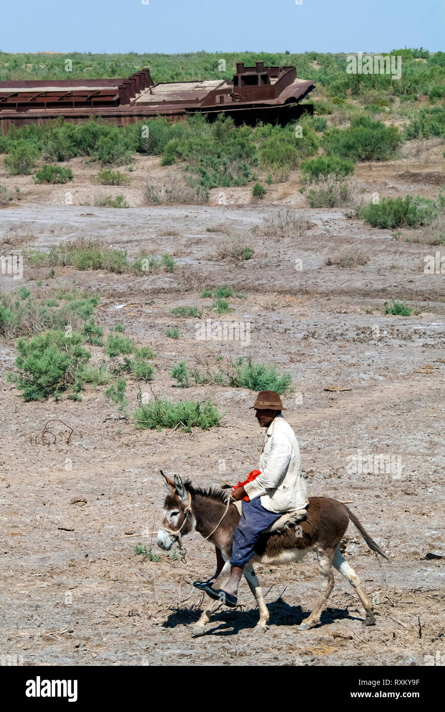 A man on a donkey rides past a stranded ship at the Aral Sea. The Aral ...