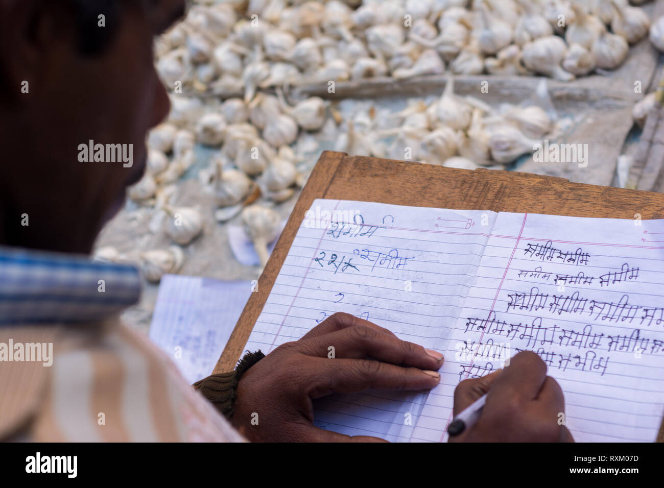 an illiterate man looking down and holding a pen in his hand and trying ...