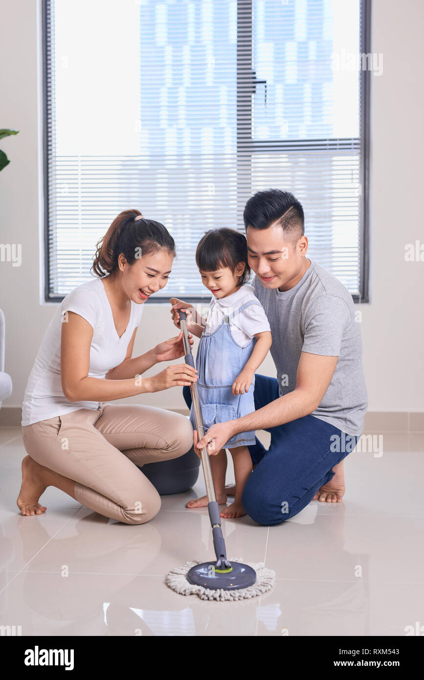 Ordinary family of three doing house cleaning with cleaning equipment ...