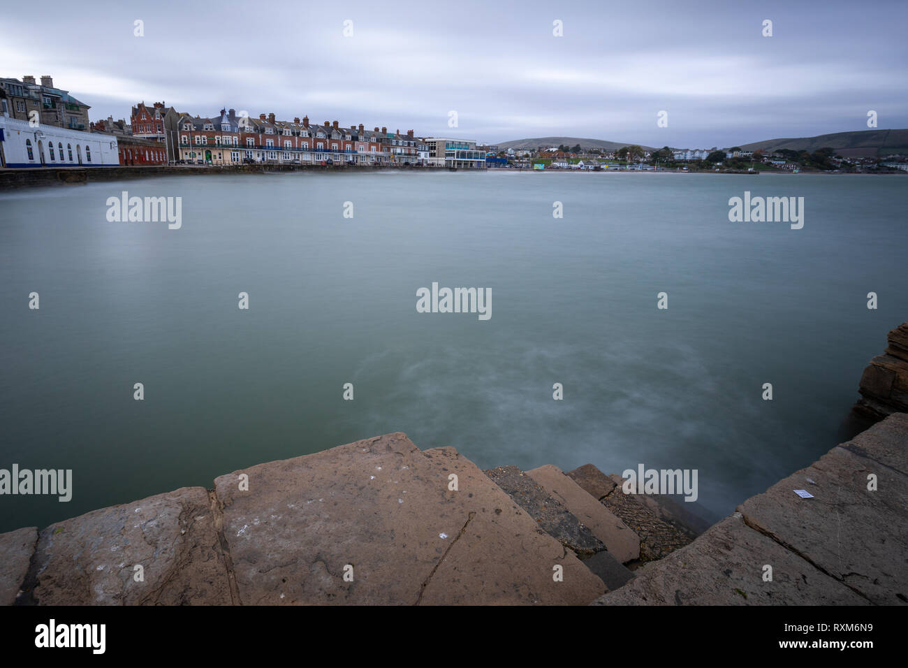 Steps from stone wharf overlooking town over bay Stock Photo - Alamy
