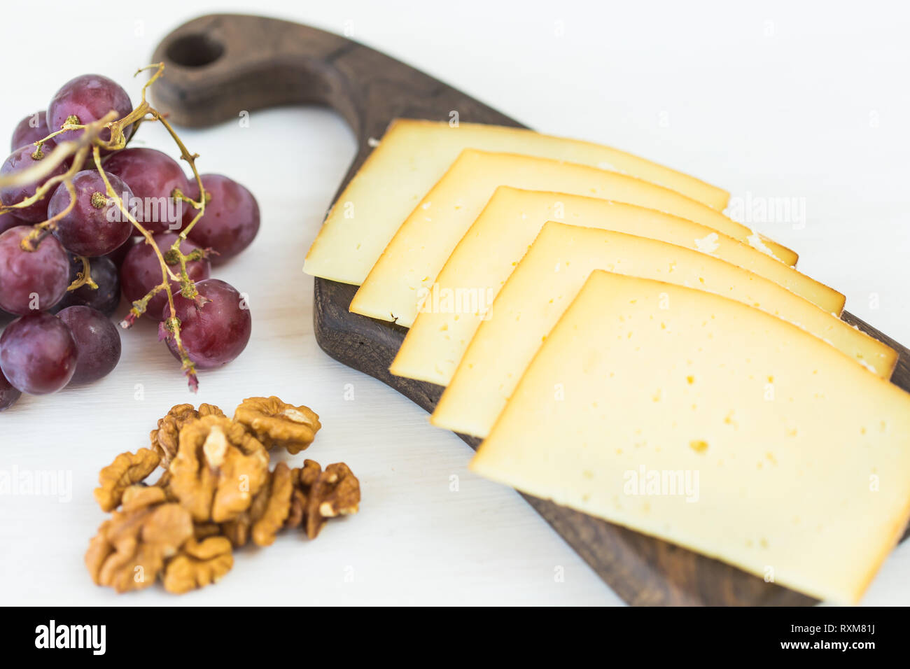 Fresh products. Sliced cheese with grapes and nuts on rustic table ...