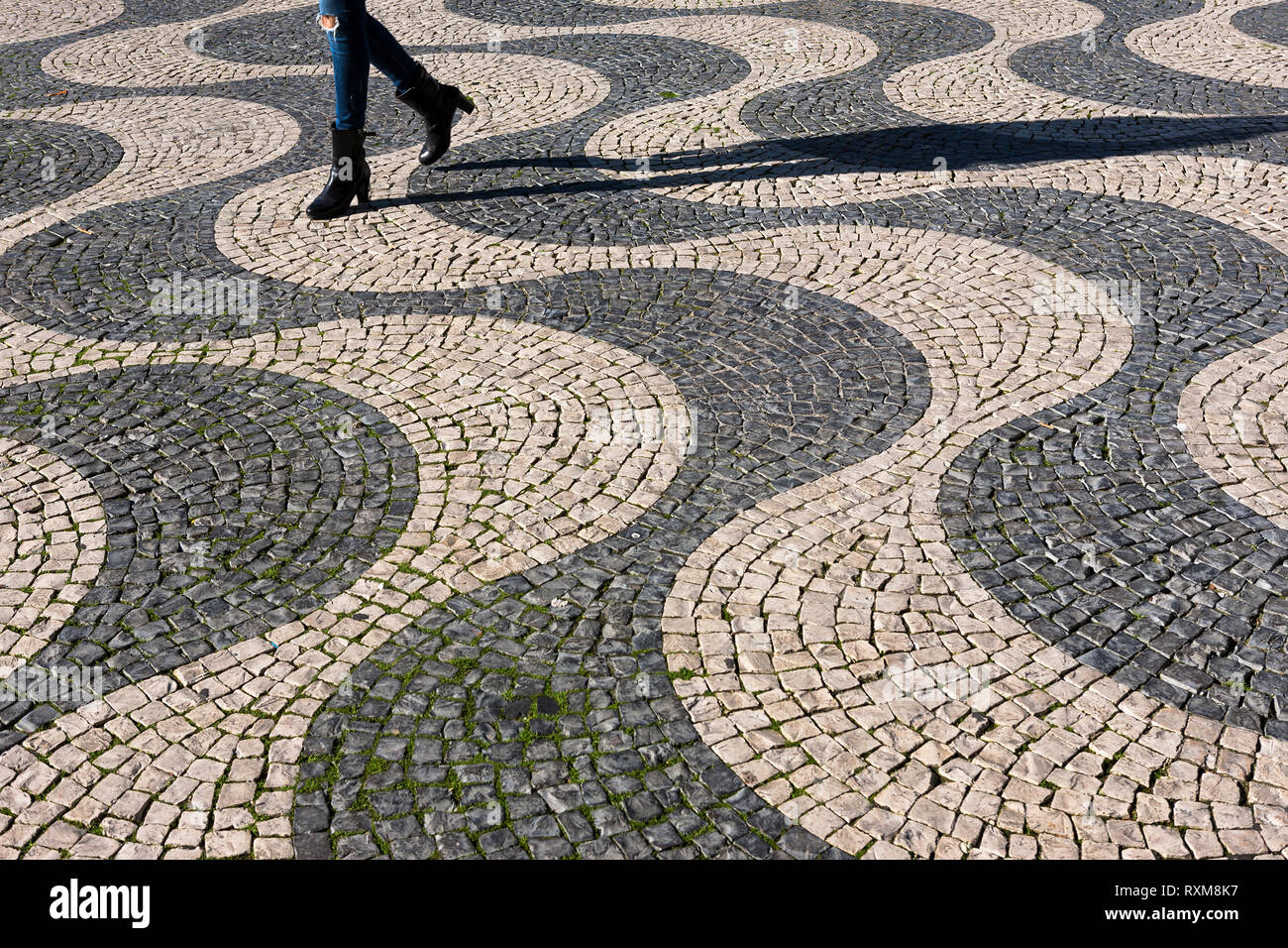 A woman's legs walk across the famous wave patterned cobblestone ...