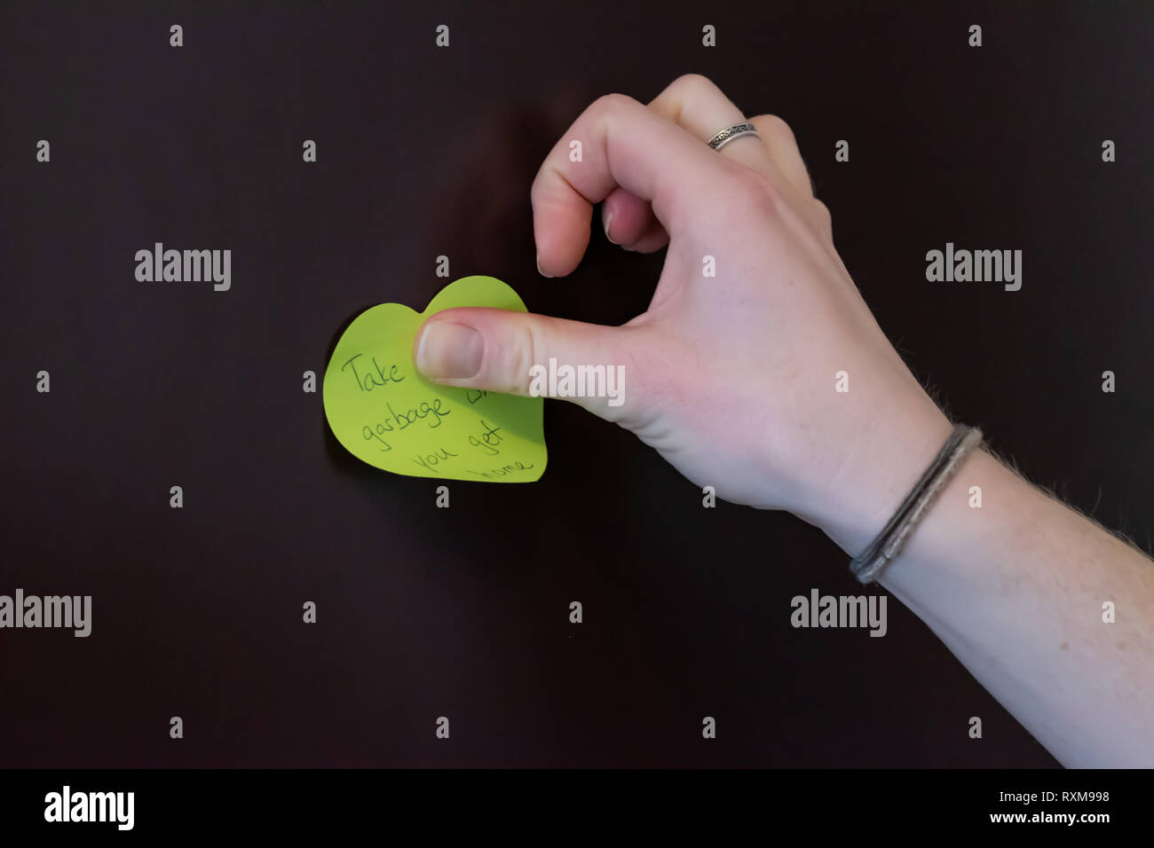 Generic green heart shaped sticky note being placed on refrigerator by ...