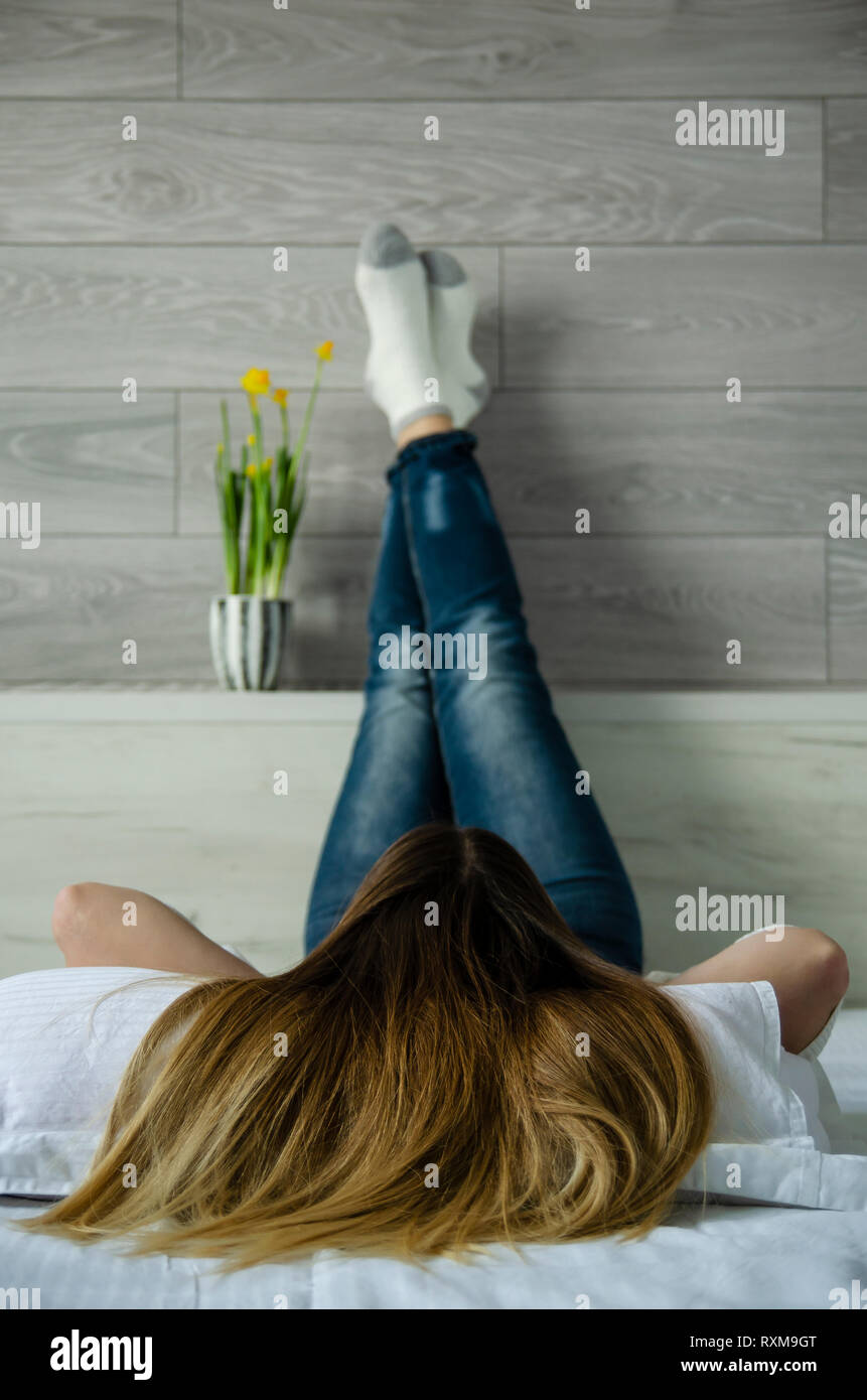 Time to have a rest. Housewife lying with her legs up on bed in the ...