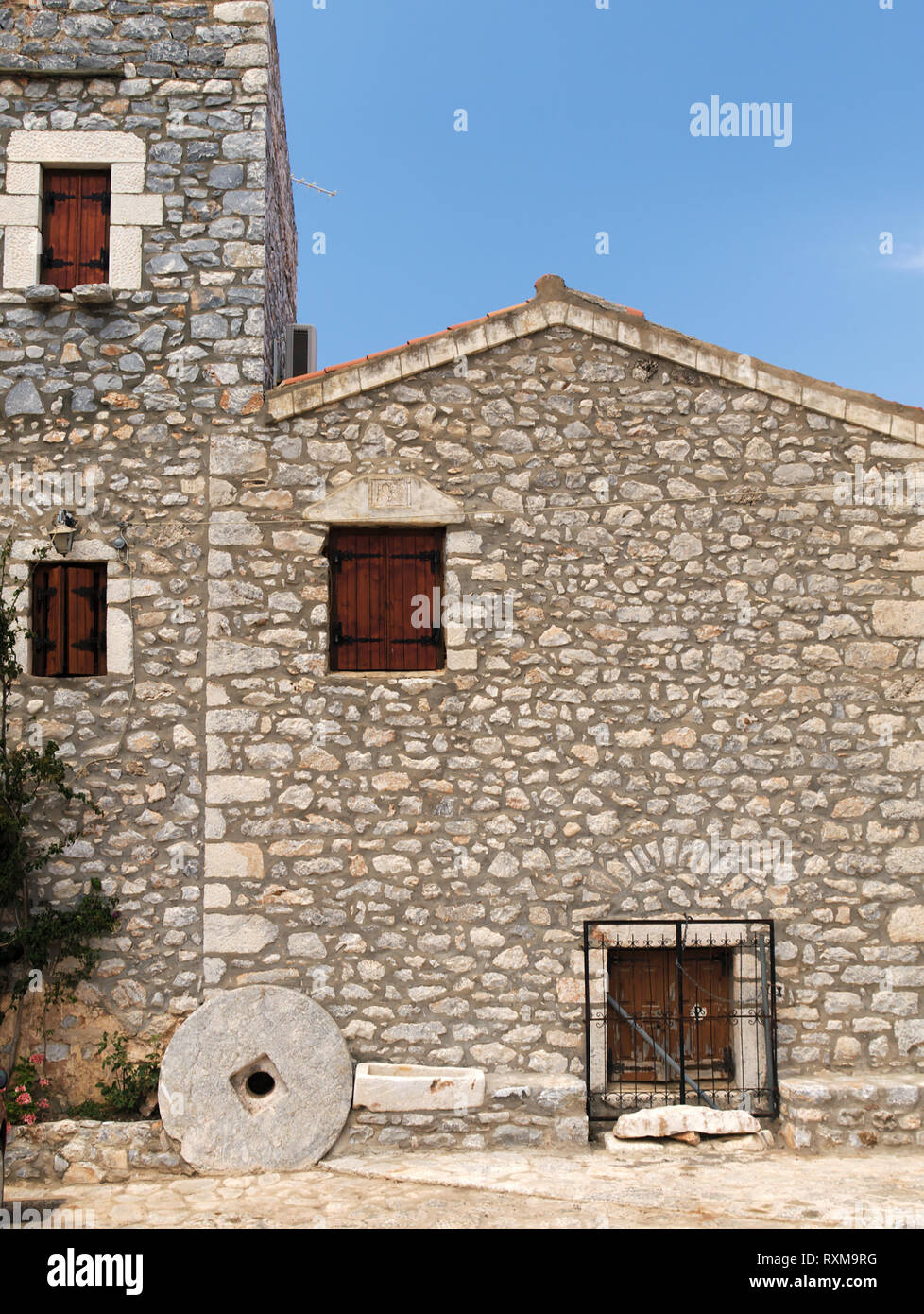 Traditional stone house with wooden windows and decorative millstone in ...