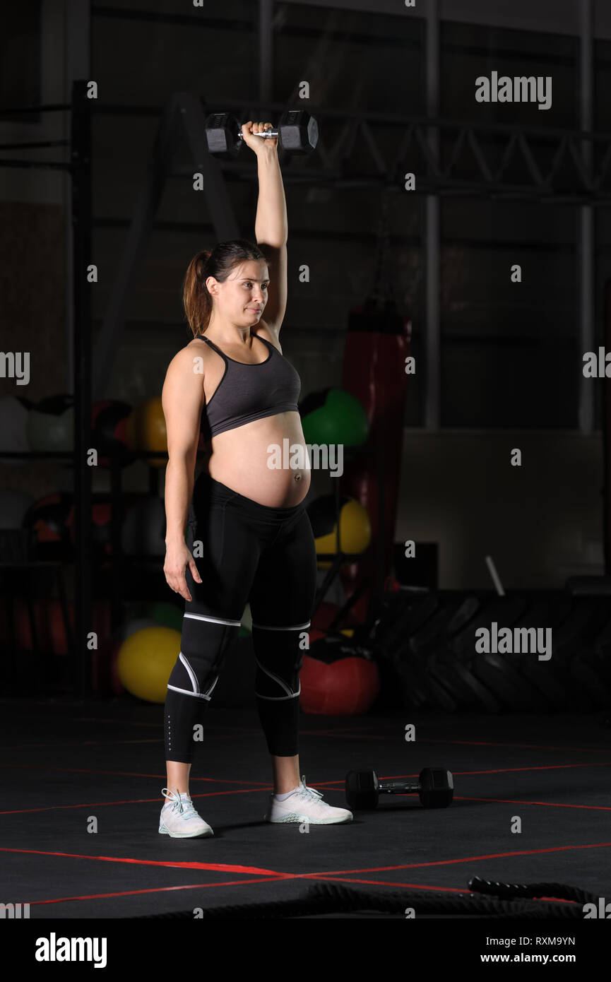 Pregnant female athlete doing dumbbell power snatch Stock Photo - Alamy