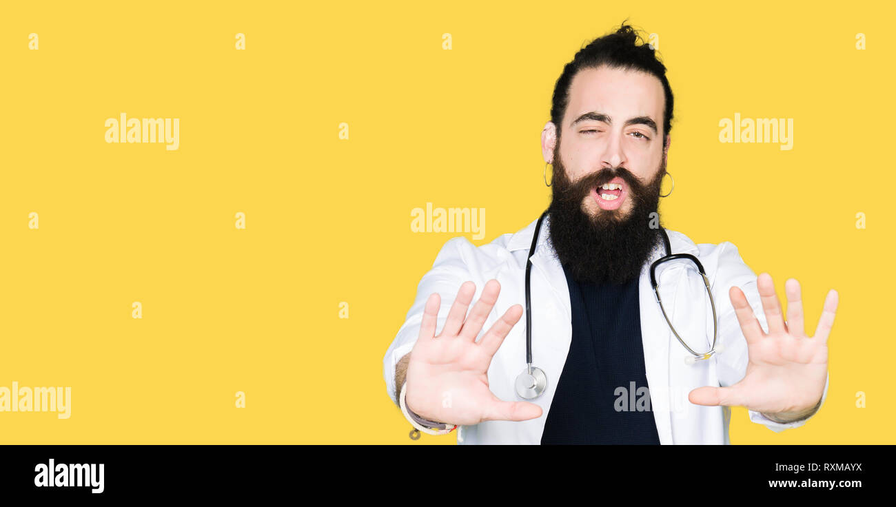 Doctor with long hair wearing medical coat and stethoscope afraid and ...