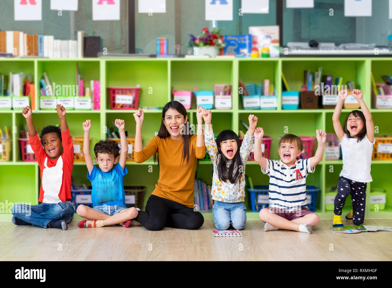 Happy Asian female teacher and mixed race kids in classroom ...