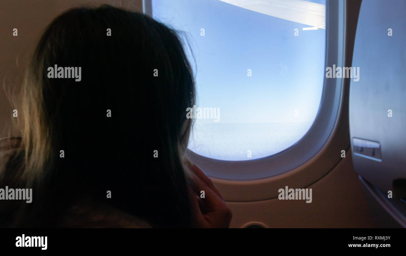 Young tween girl staring out airplane window Stock Photo - Alamy