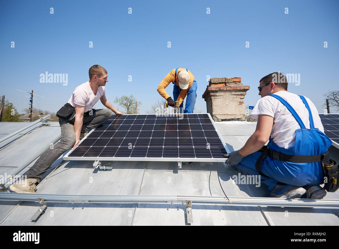 Male workers installing stand-alone solar photovoltaic panel system ...