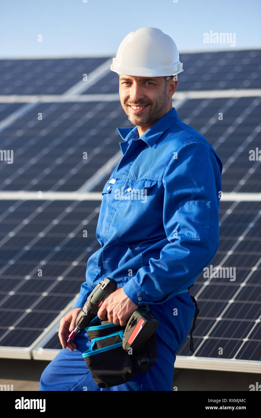 Portrait of male worker in blue suit and protective helmet installing ...
