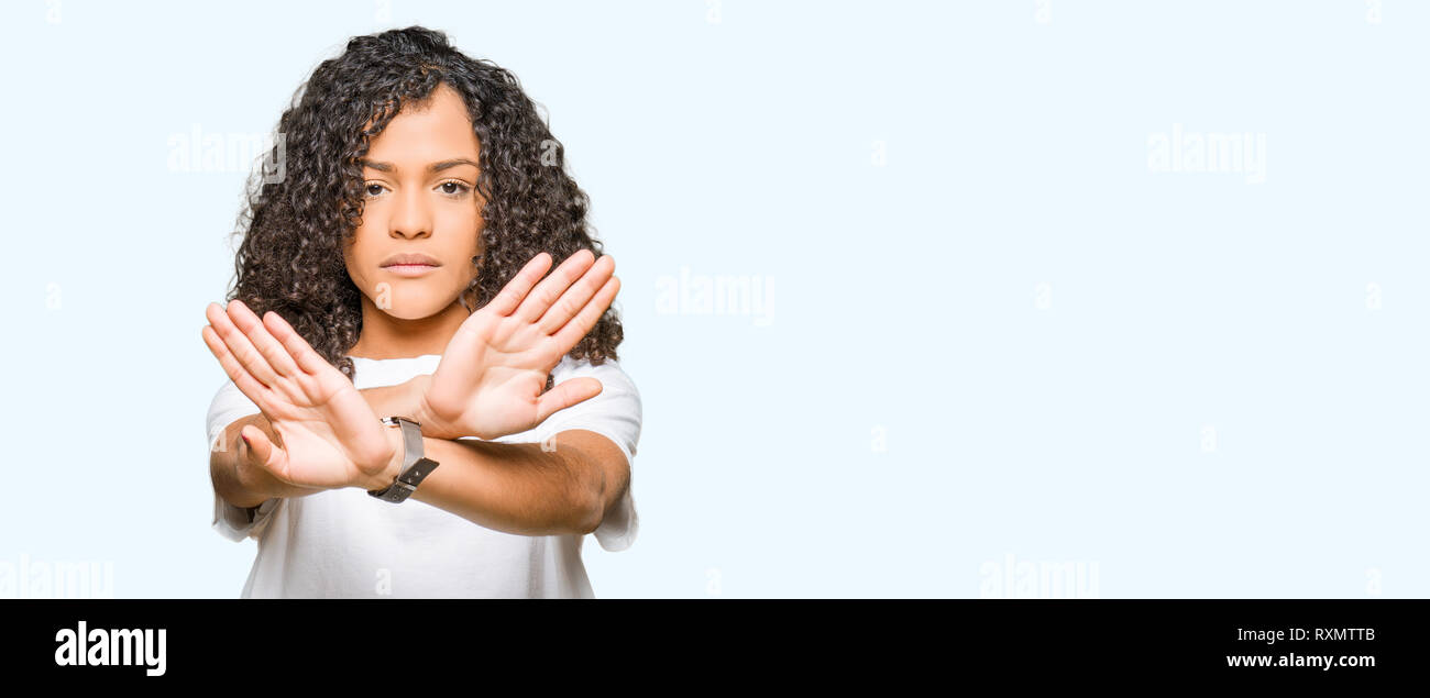 Young beautiful woman with curly hair wearing white t-shirt Rejection ...