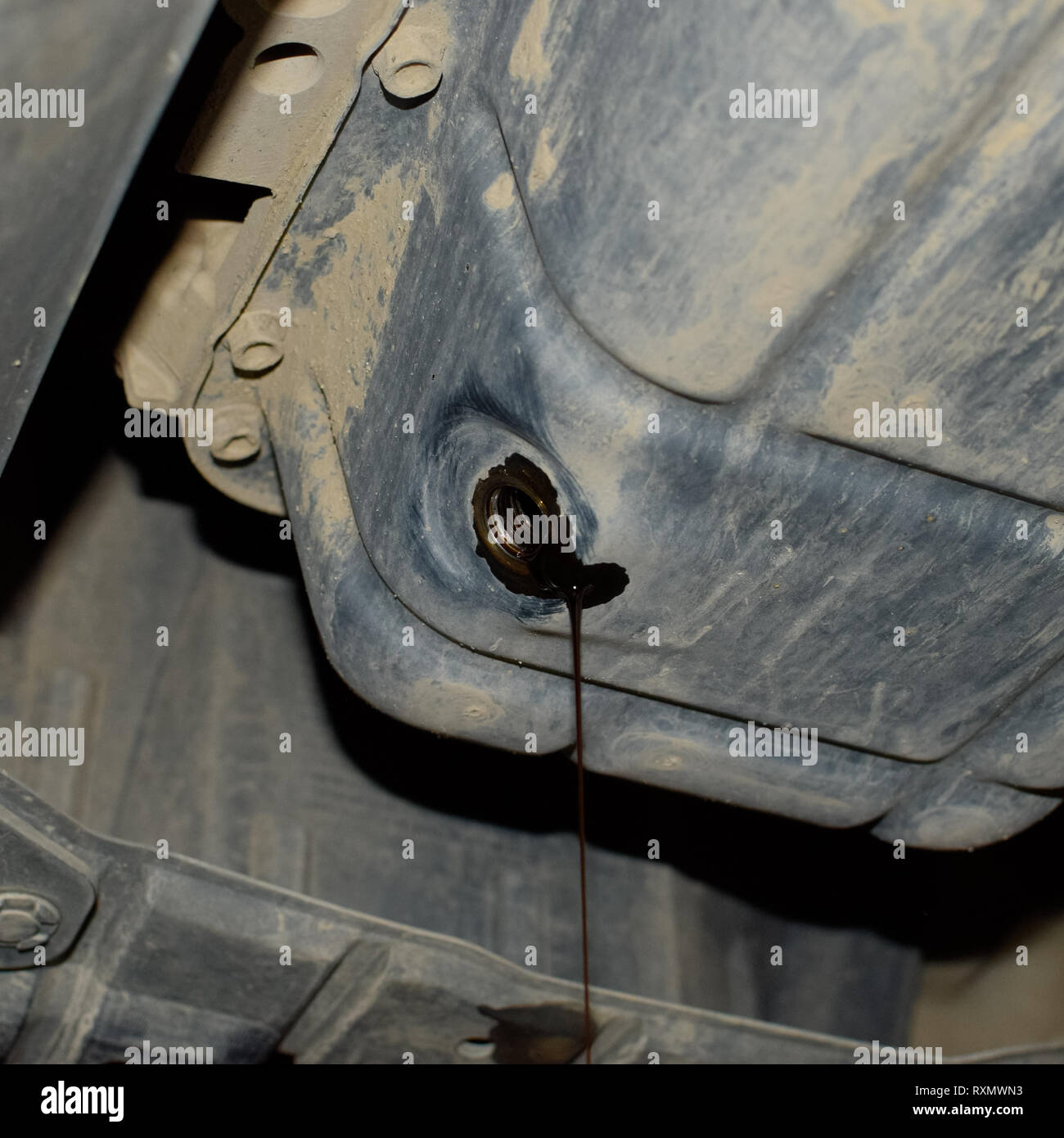 Drain the old oil from the engine through the drain plug. Changing the oil in a car engine Stock ...