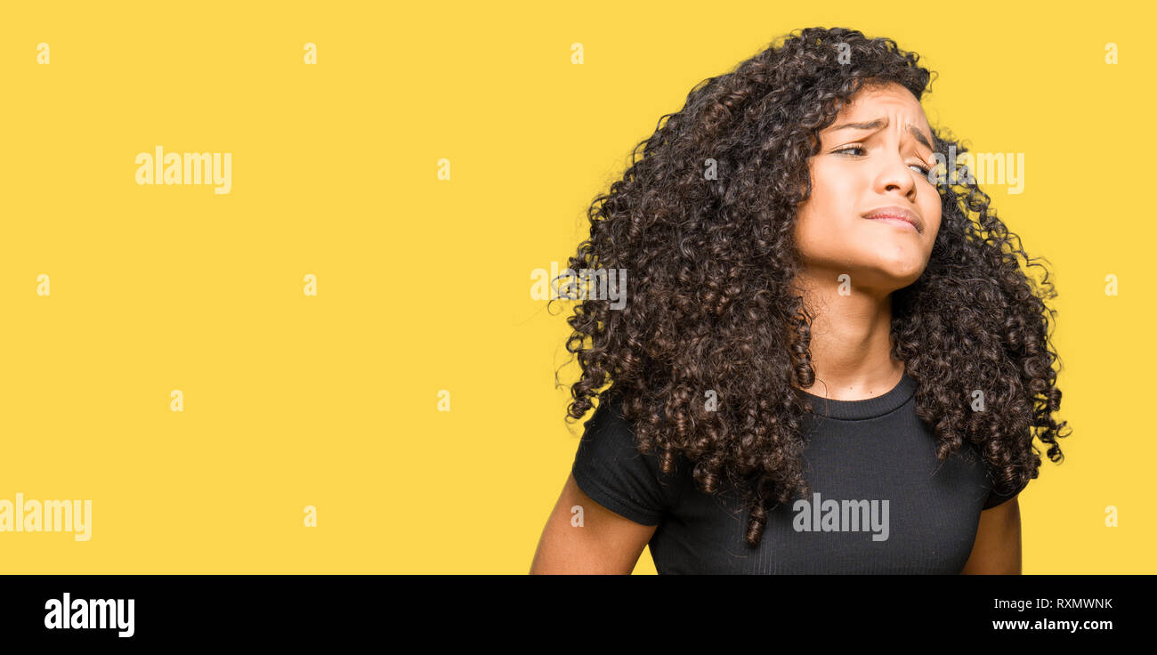 Young beautiful woman with curly hair with hand on stomach because ...