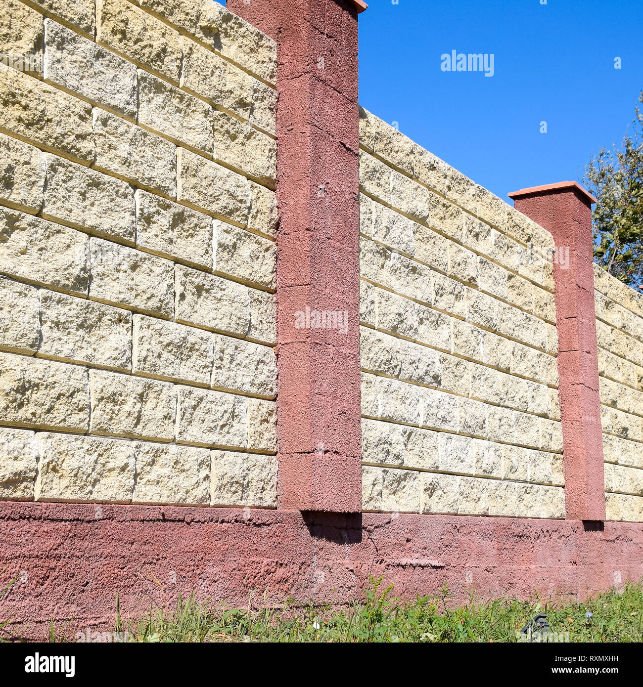 Fence made of bricks and decorative plaster. Yellow fence with red ...