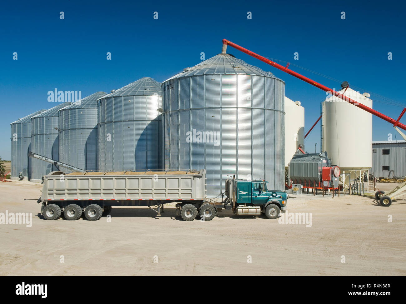 a farm truck next to grain storage bins in a farmyard, near Lorette ...