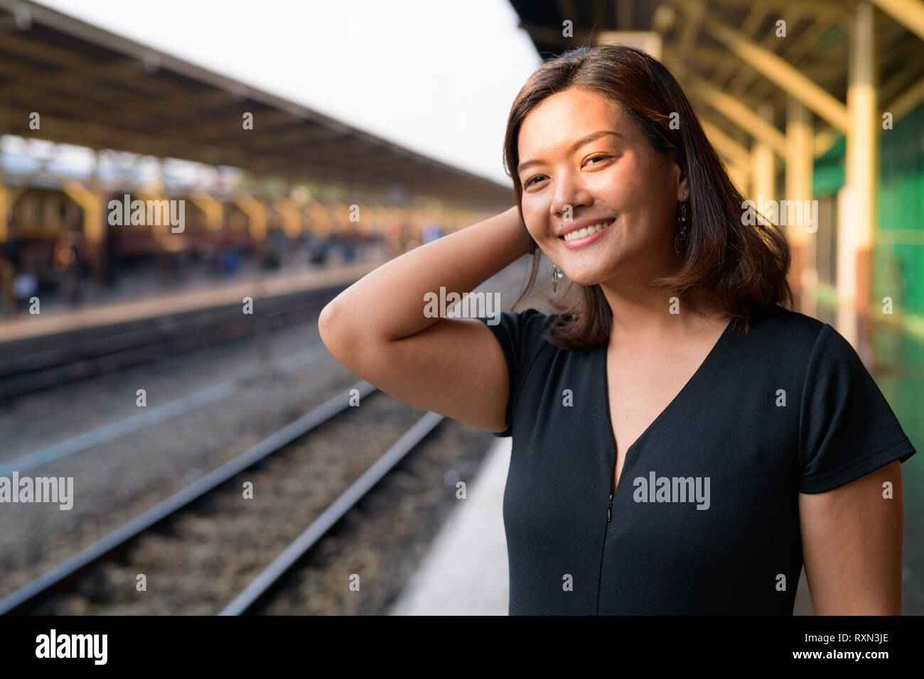 Young happy Asian tourist woman thinking at the railway station Stock Photo - Alamy