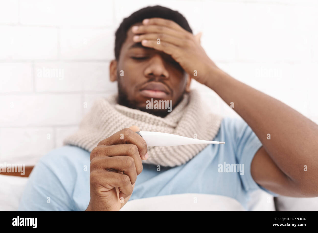 Sick african-american man measuring body temperature in bed Stock Photo ...