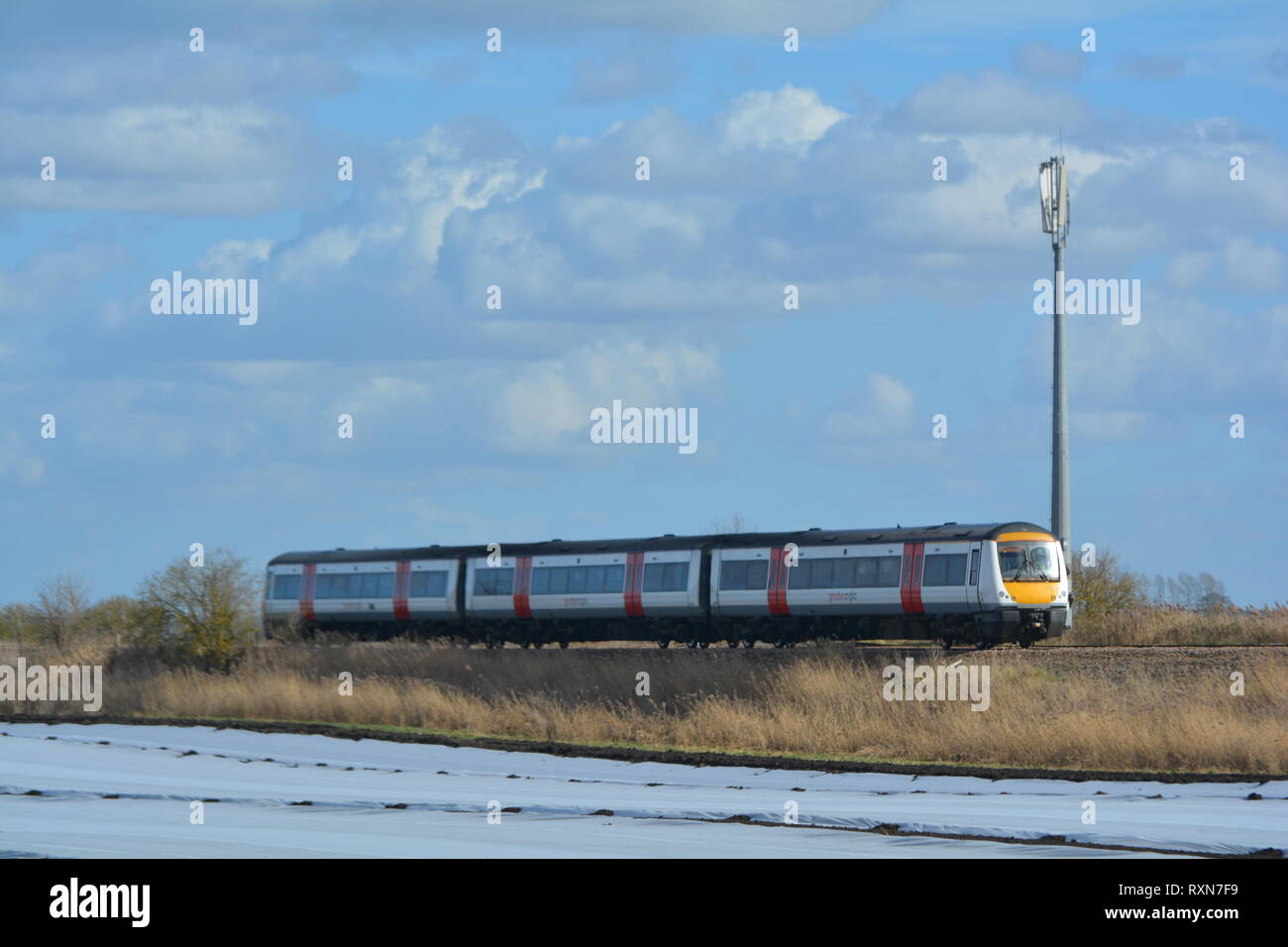 Modern passenger train running through the fens near elysee on a bright ...