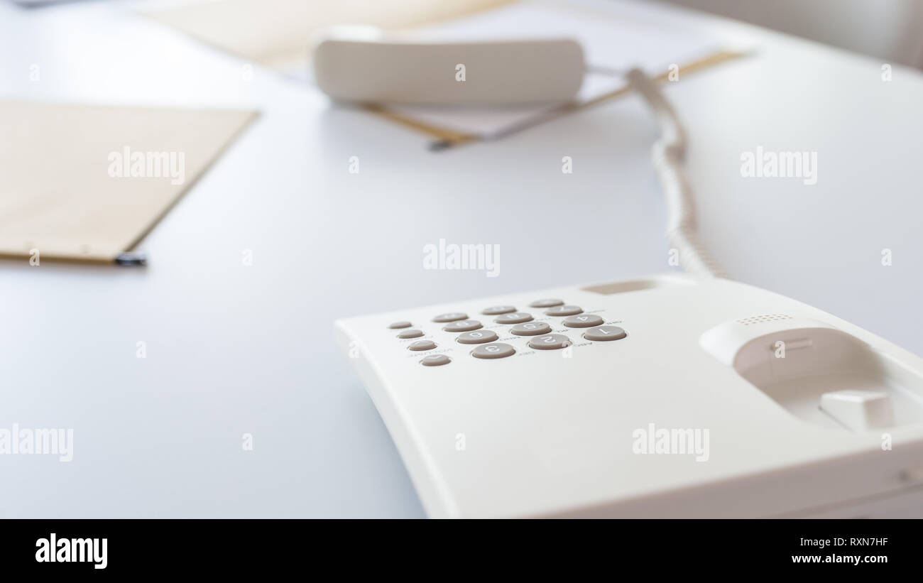 Landline telephone with handset of the hook on an office desk with ...