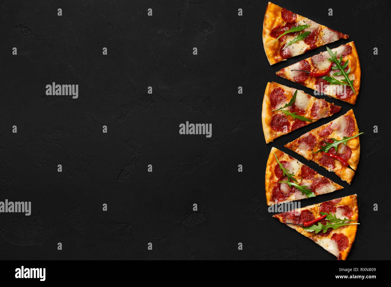 Fresh pepperoni pizza slices in row on dark background Stock Photo - Alamy