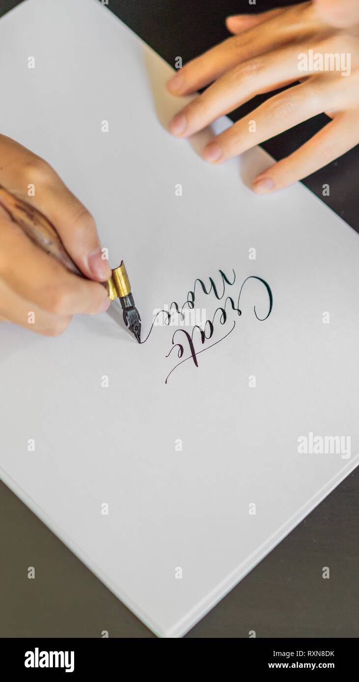 Calligrapher hands writes phrase on white paper. Phrase - Create more ...