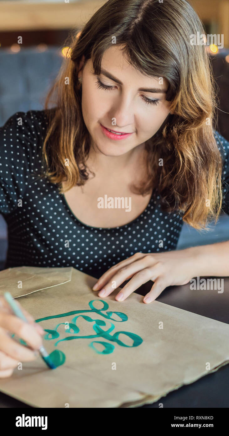 Calligrapher Young Woman writes phrase on white paper. Go green ...