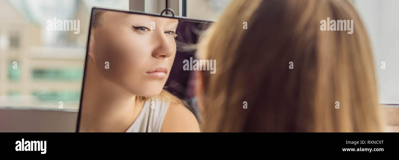 Young woman does makeup sitting by the window with a panoramic view of ...